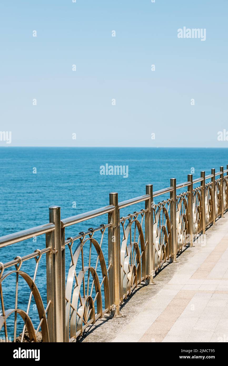 Long metal fence on paved waterfront near rippling sea against ...
