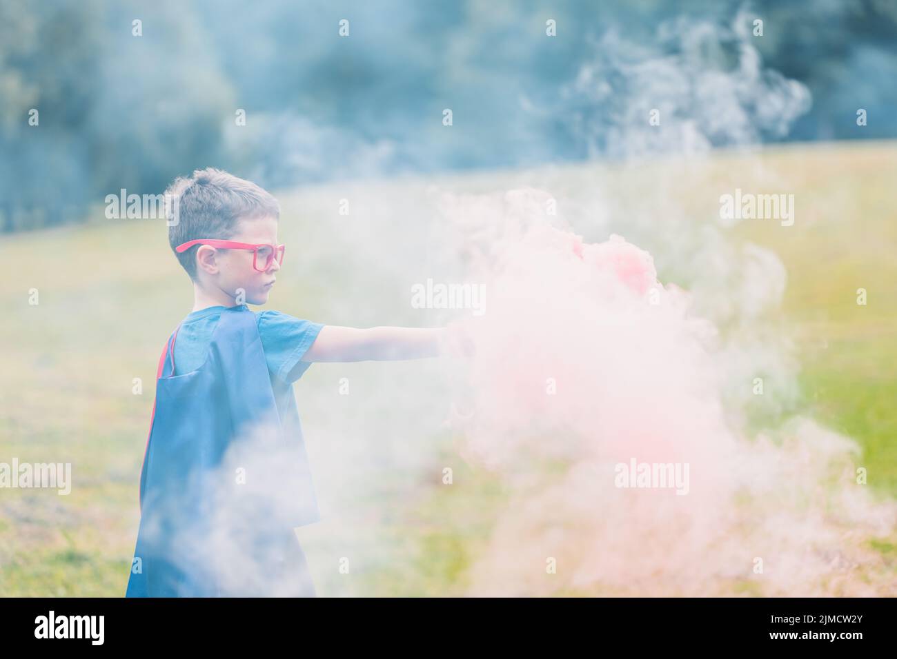 Side view of cute boy in superhero costume and glasses holding red ...