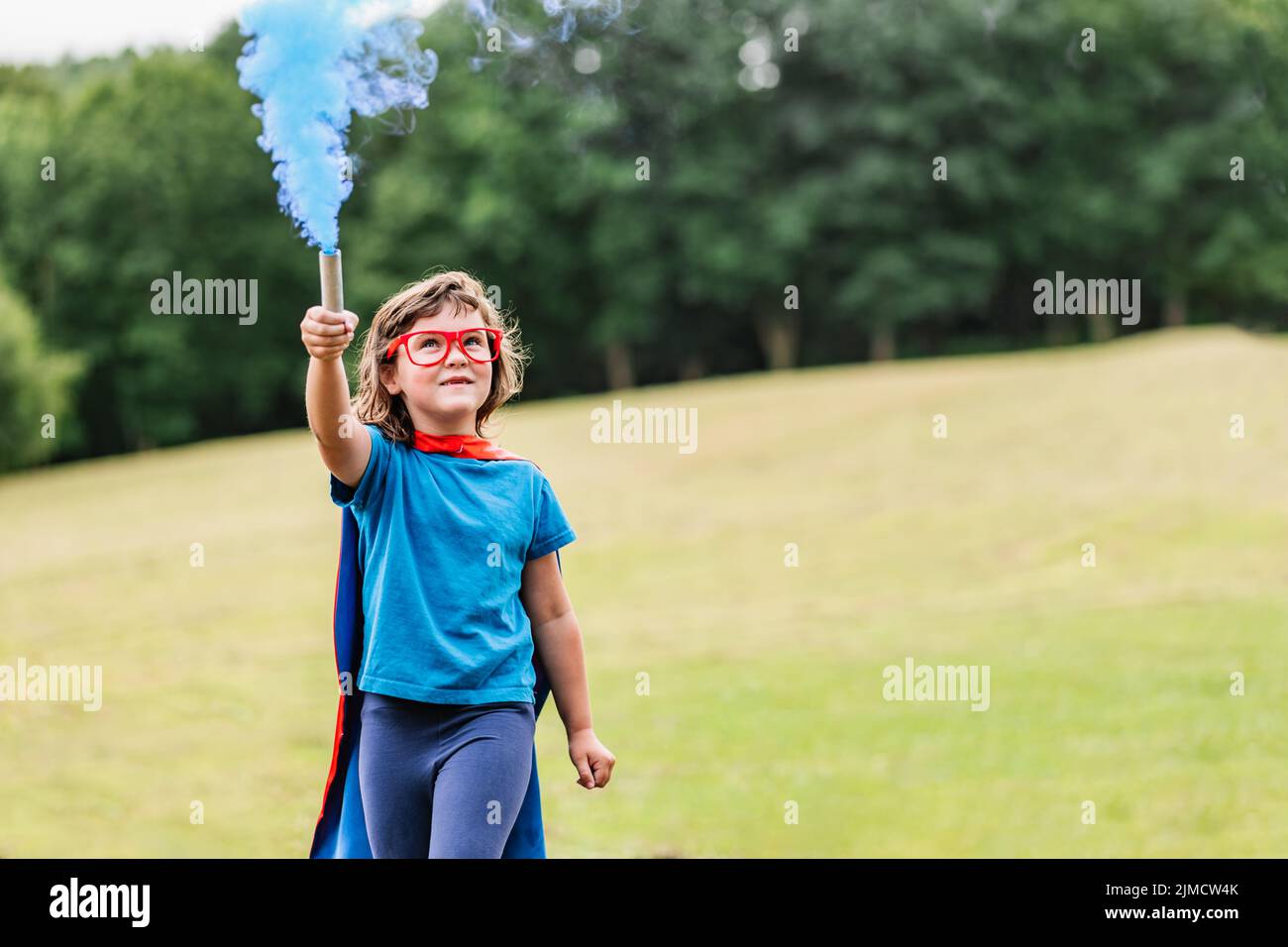 Girl in superhero costume waving hand with blue smoke bomb while ...
