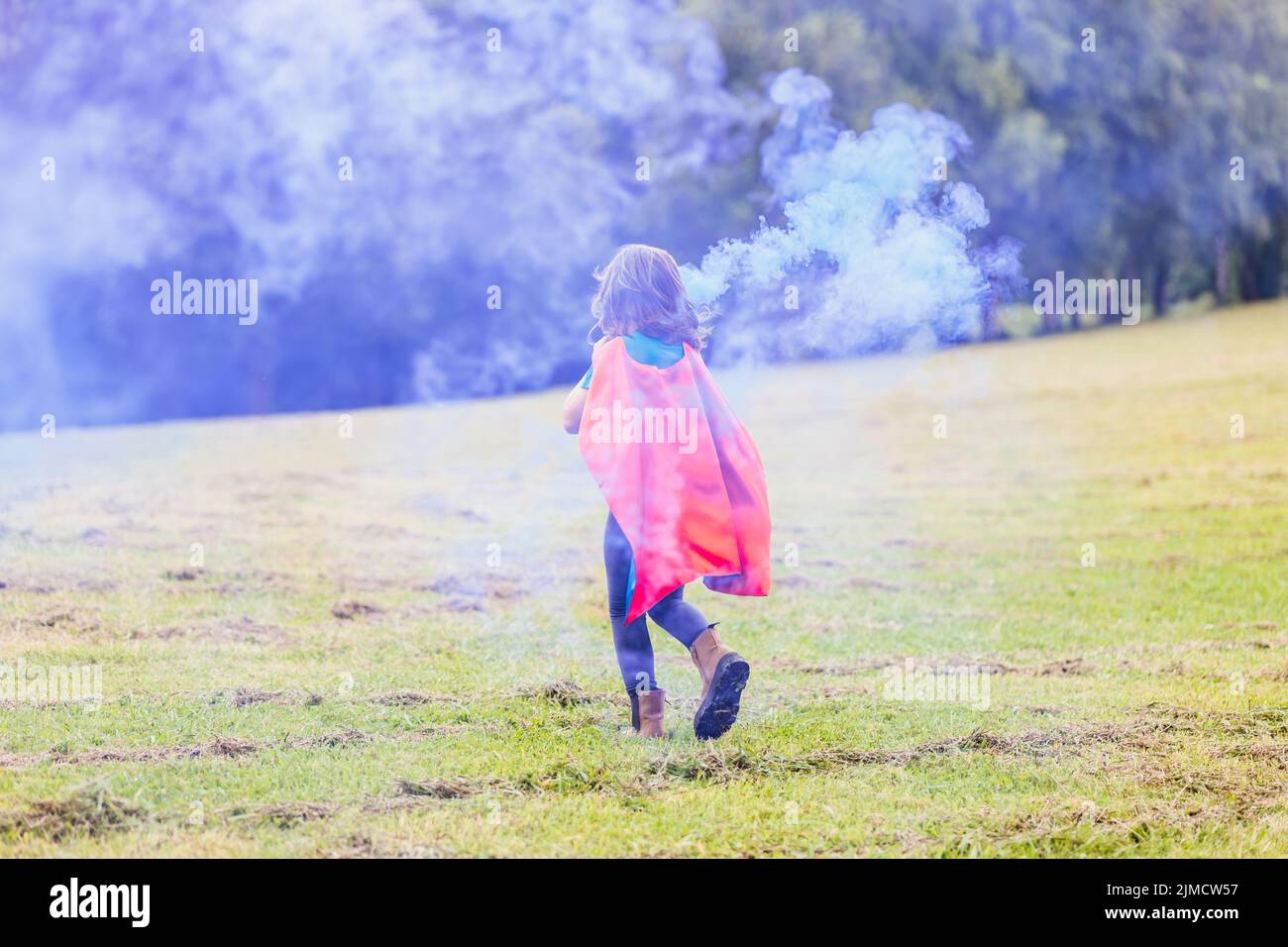 Back view of cute excited girl in superhero costume and glasses holding ...