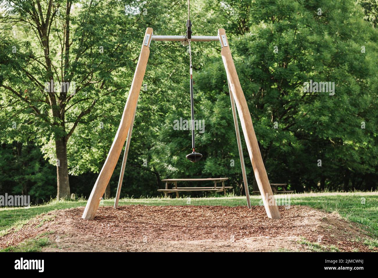Zipline swing installed on playground against lush trees on summer day ...