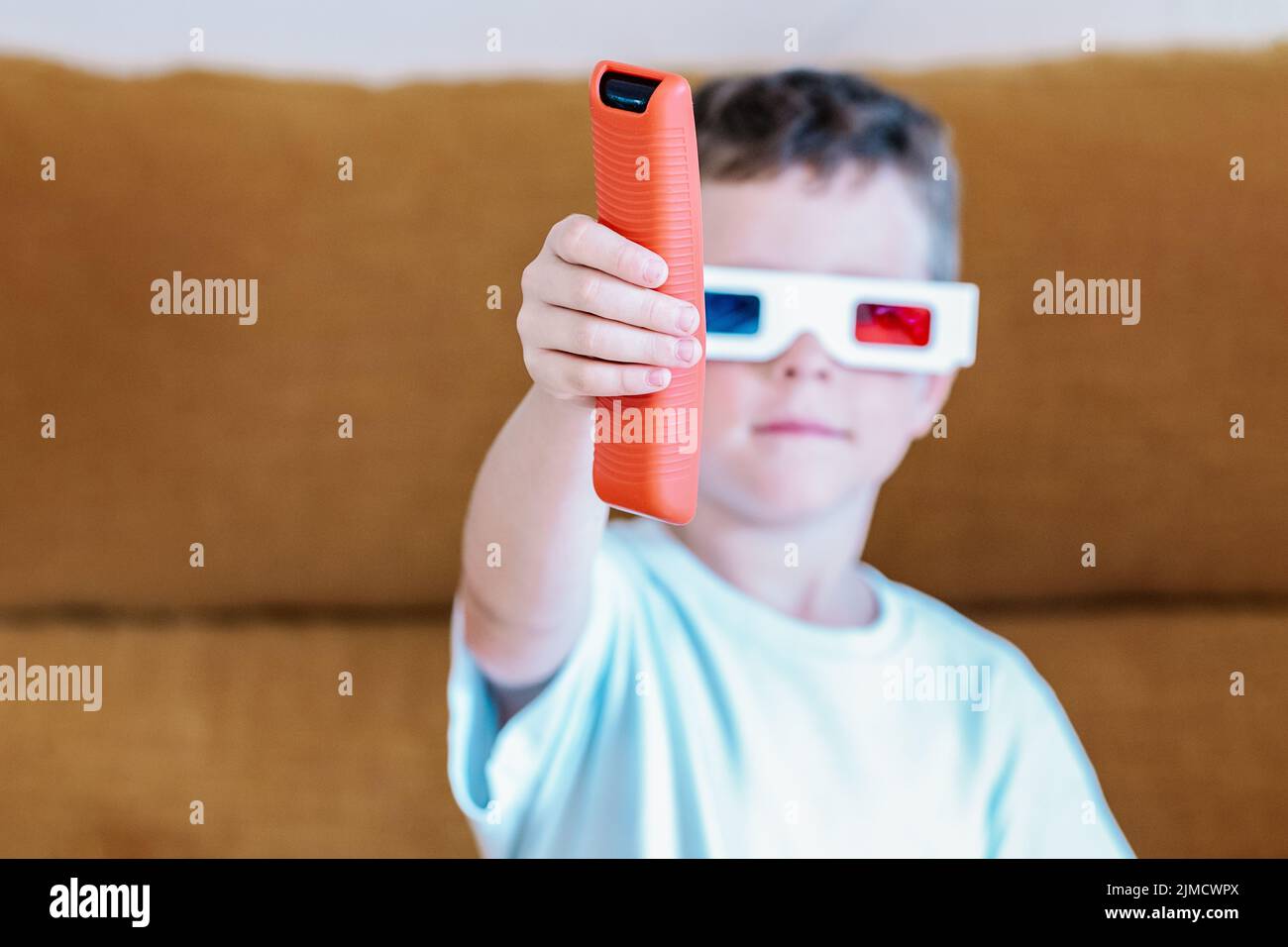 Focused child in colorful 3D glasses changing channels with remote ...