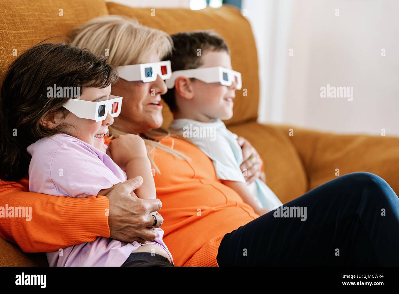Side view of mother with children in 3D glasses watching interesting ...