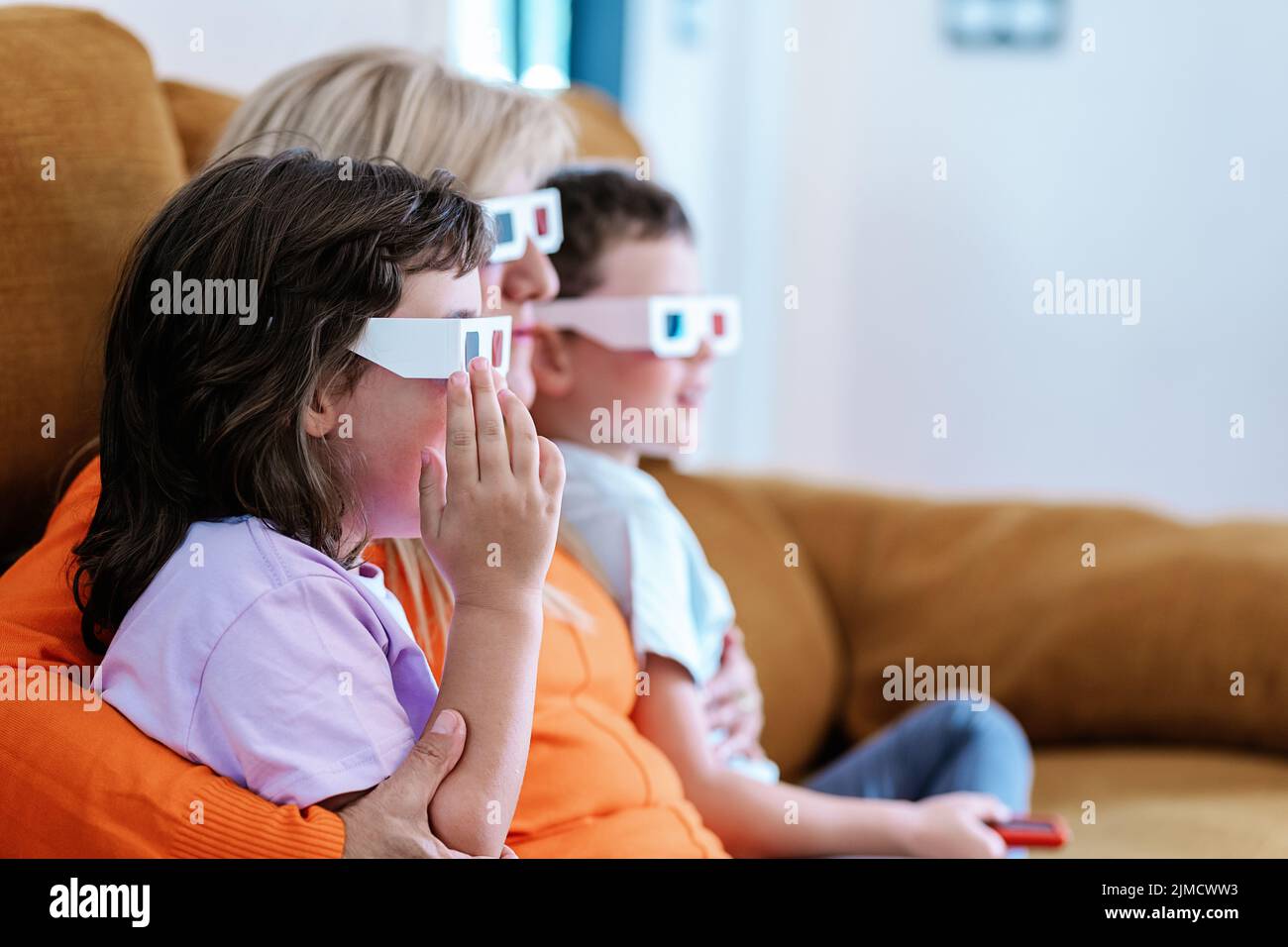 Side view of mother with children in 3D glasses watching interesting ...