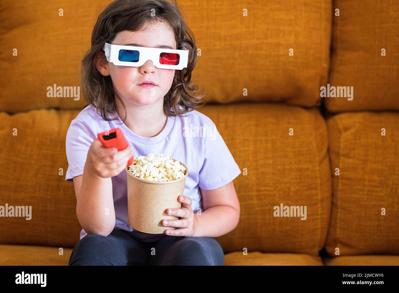 Kid changing channels while watching movie in 3D glasses on couch with ...