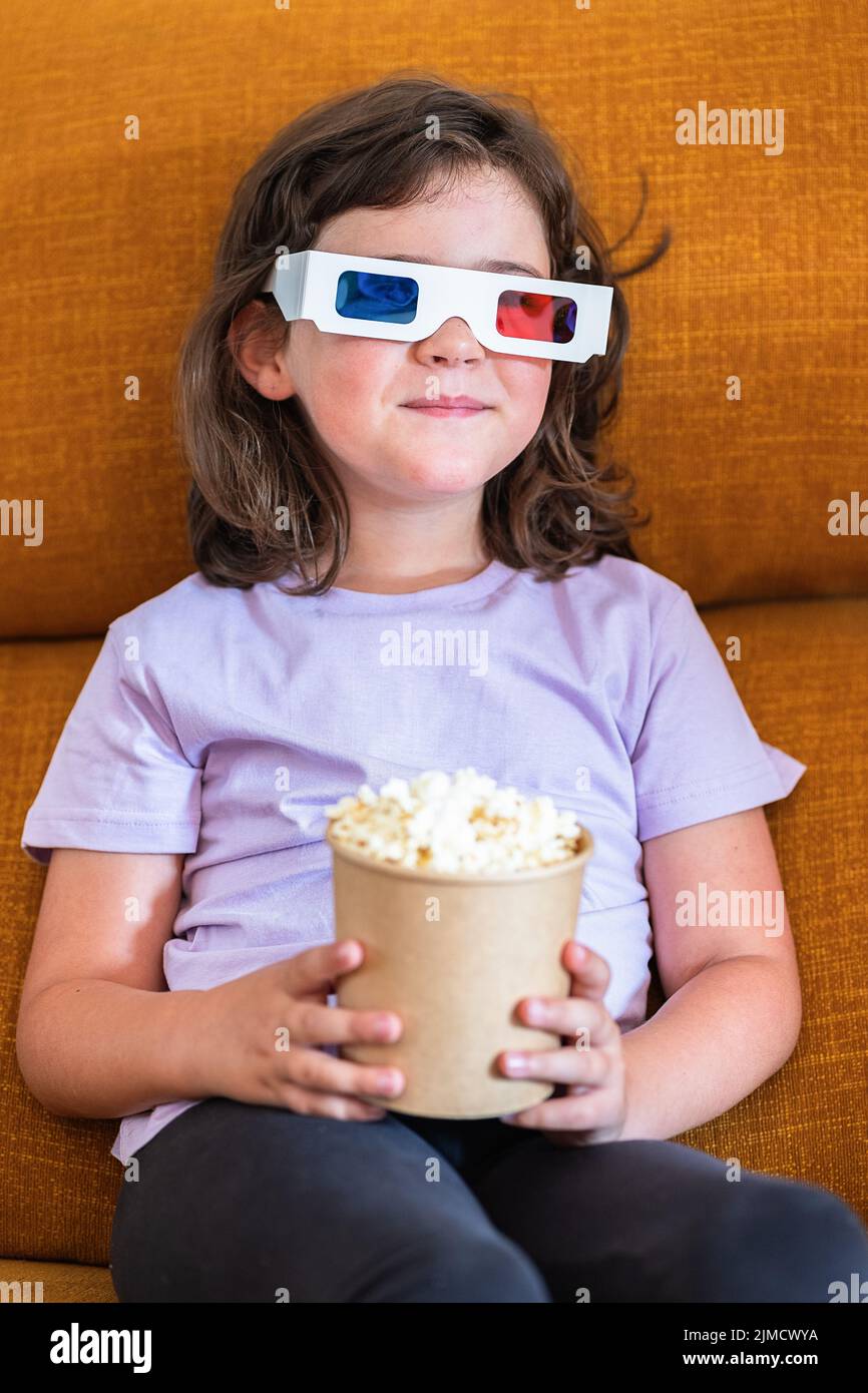 Kid changing channels while watching movie in 3D glasses on couch with ...