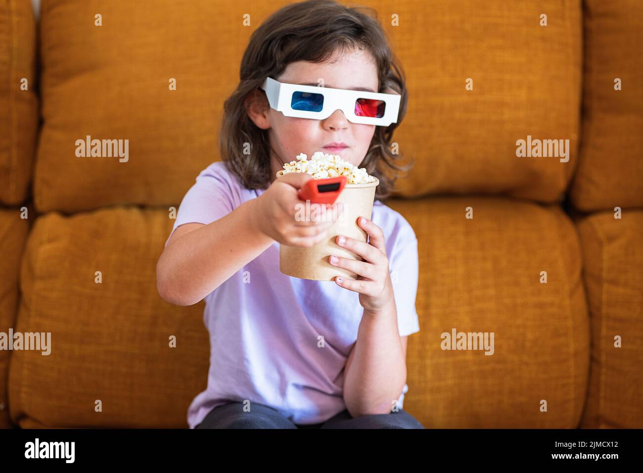 Kid changing channels while watching movie in 3D glasses on couch with ...