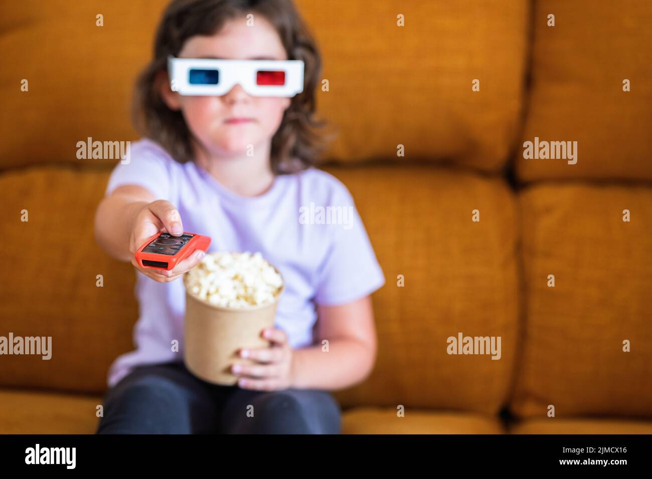 Kid changing channels while watching movie in 3D glasses on couch with ...