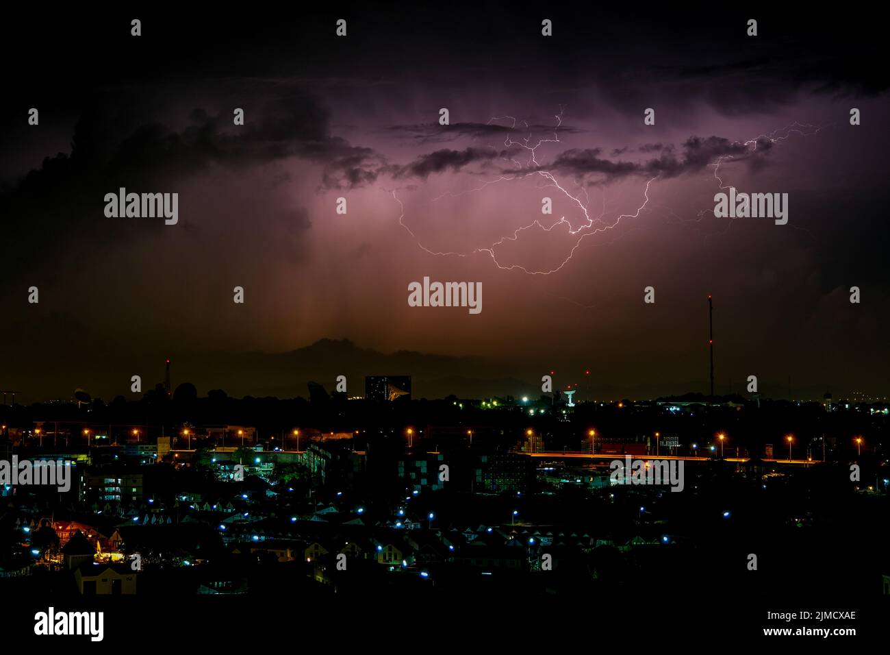 Bright lightning bolt strikes in the rural landscape of small city and ...