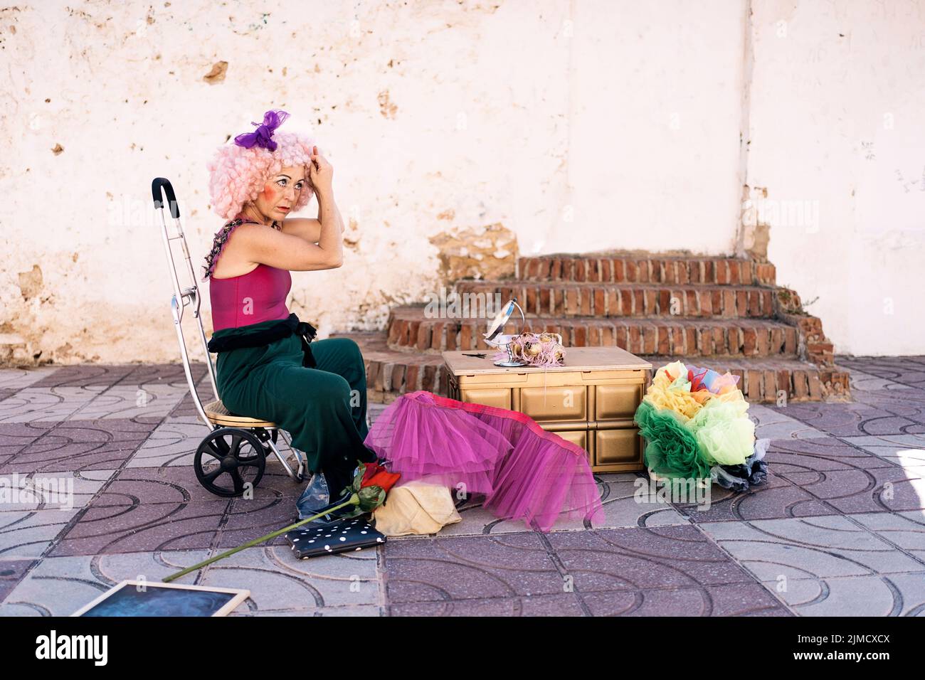 Side view of concentrate middle aged female clown with bright makeup in ...