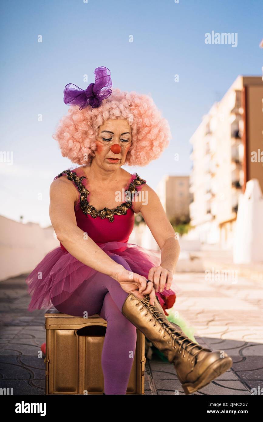 Concentrated middle aged female circus artist in funny costume and pink ...
