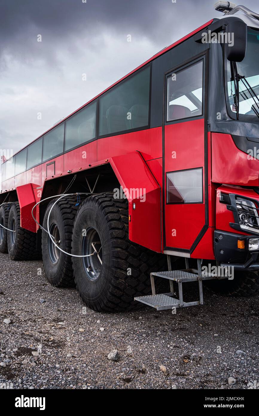 Modern red glacial expedition bus with steps and large wheels parked on ...