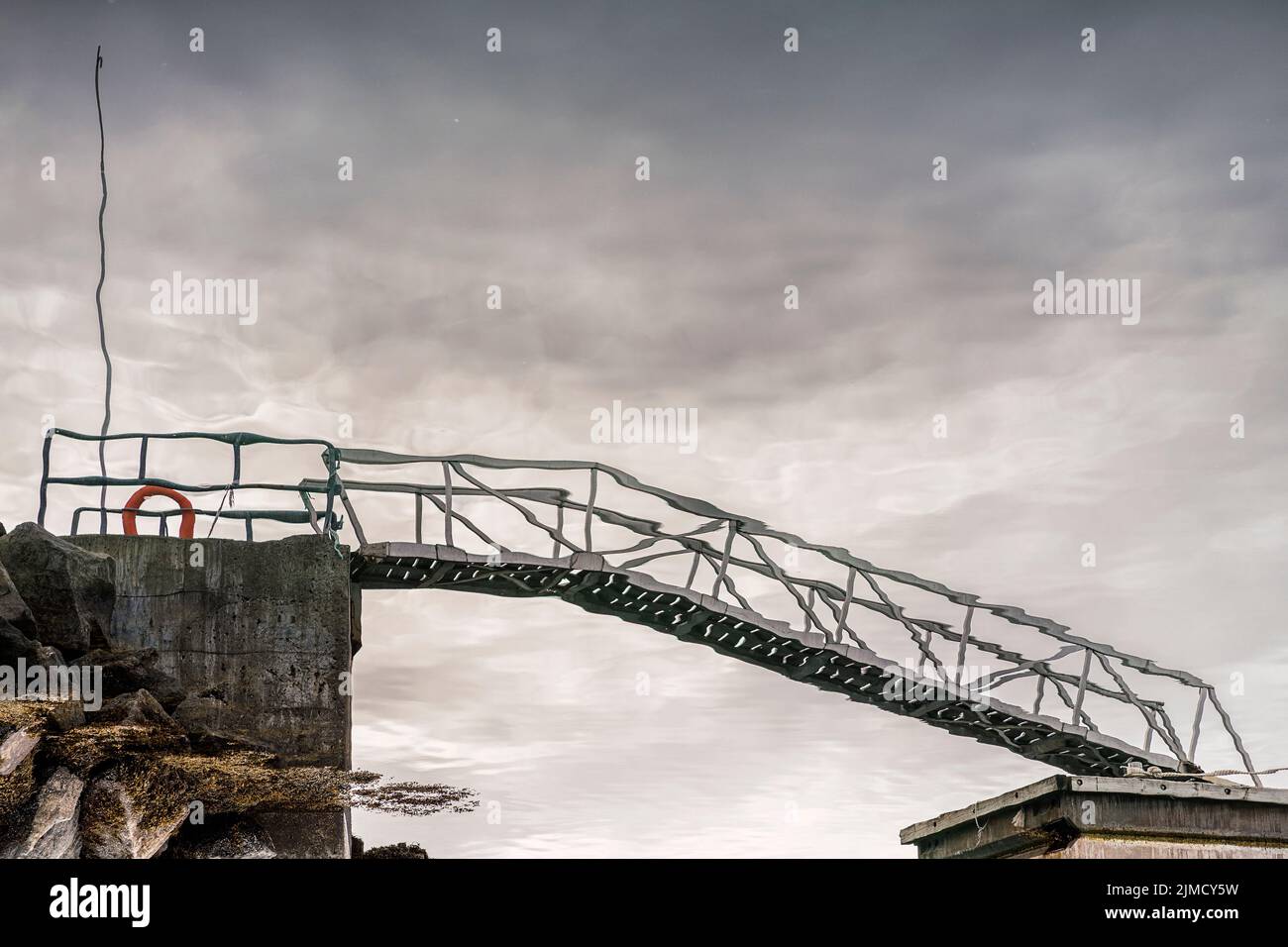 Metal gangway with lifebuoy and cloudy sky reflecting in clean sea ...