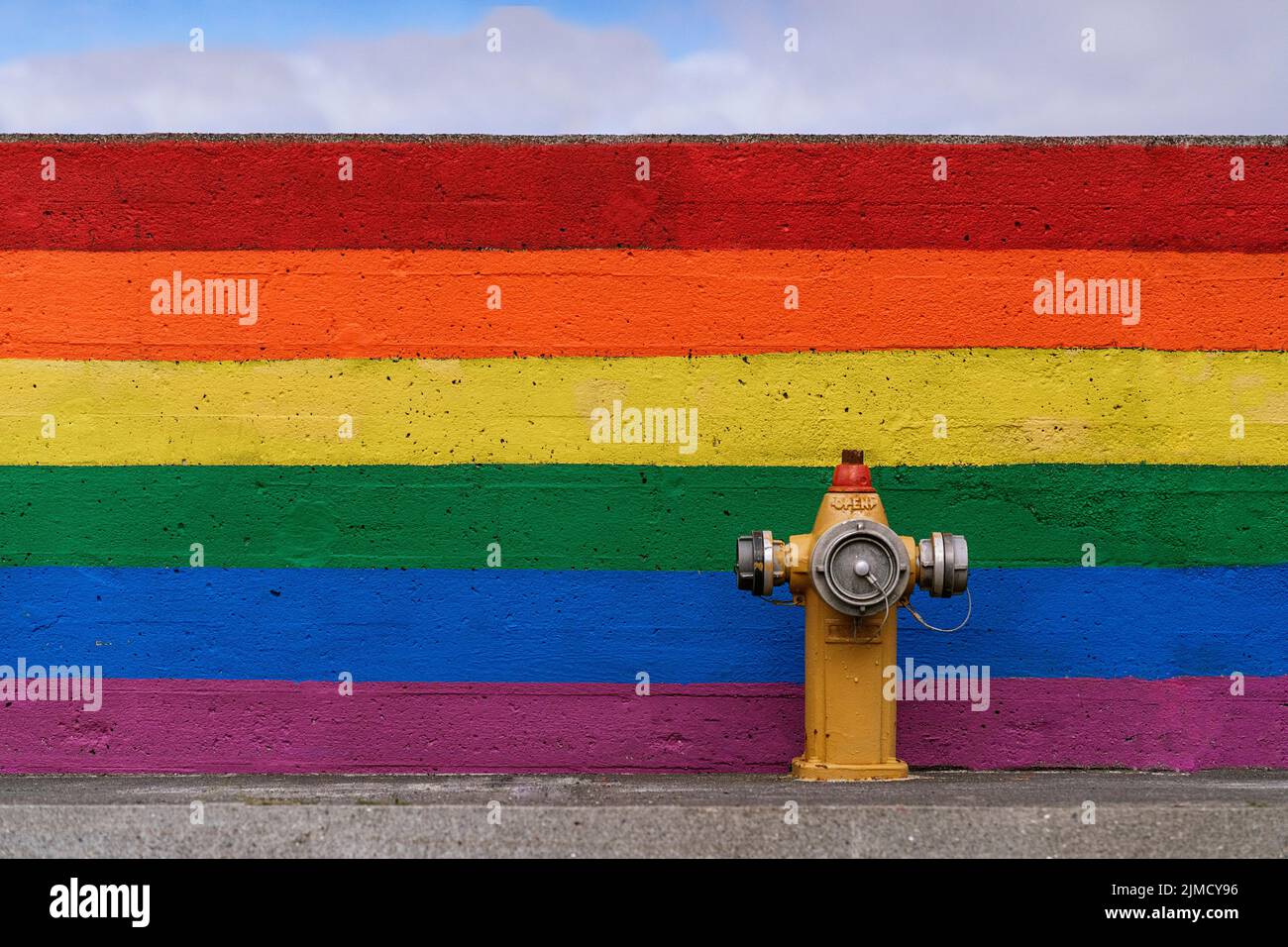 Traditional fire hydrant on street near wall with painted LGBT rainbow ...