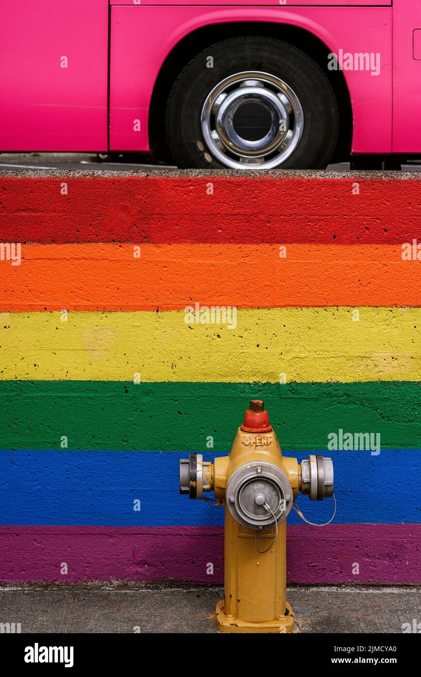 Traditional fire hydrant on street near wall with painted LGBT rainbow ...
