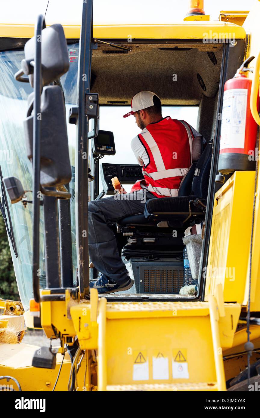 Side view of combine operator in uniform harvesting grain crops in ...