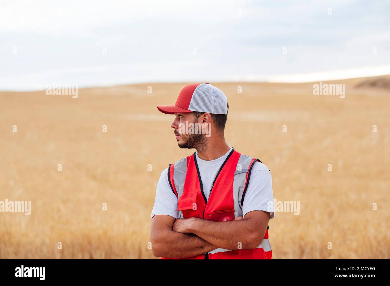 Serious male farmer in uniform standing in agricultural plantation with ...