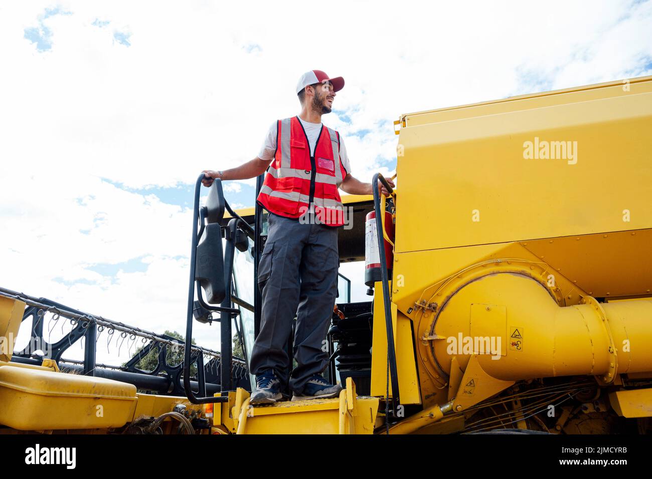 From below full body side of pensive male combine operator in uniform ...