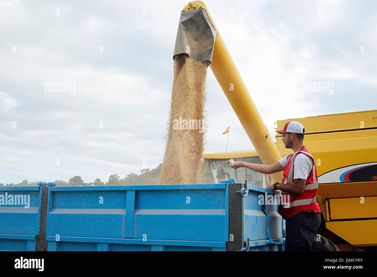 Side view of male farmer standing near industrial combine harvester ...