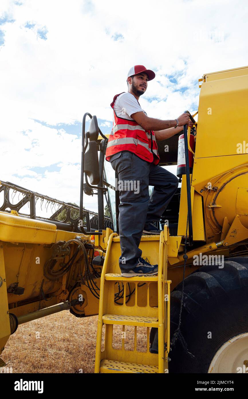 From below full body side of pensive male combine operator in uniform ...
