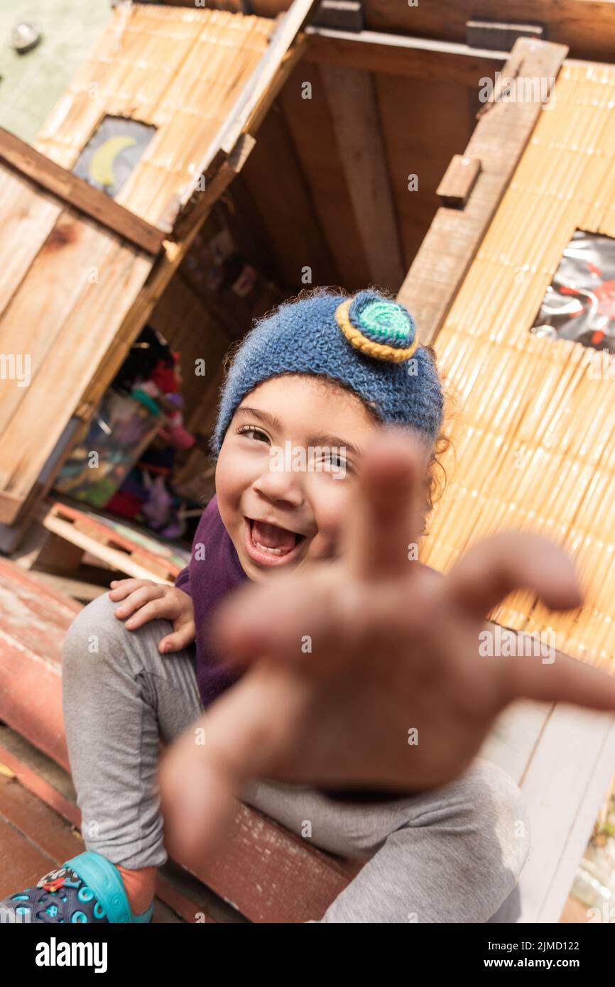 Delighted ethnic girl reaching out hand and looking at camera with ...