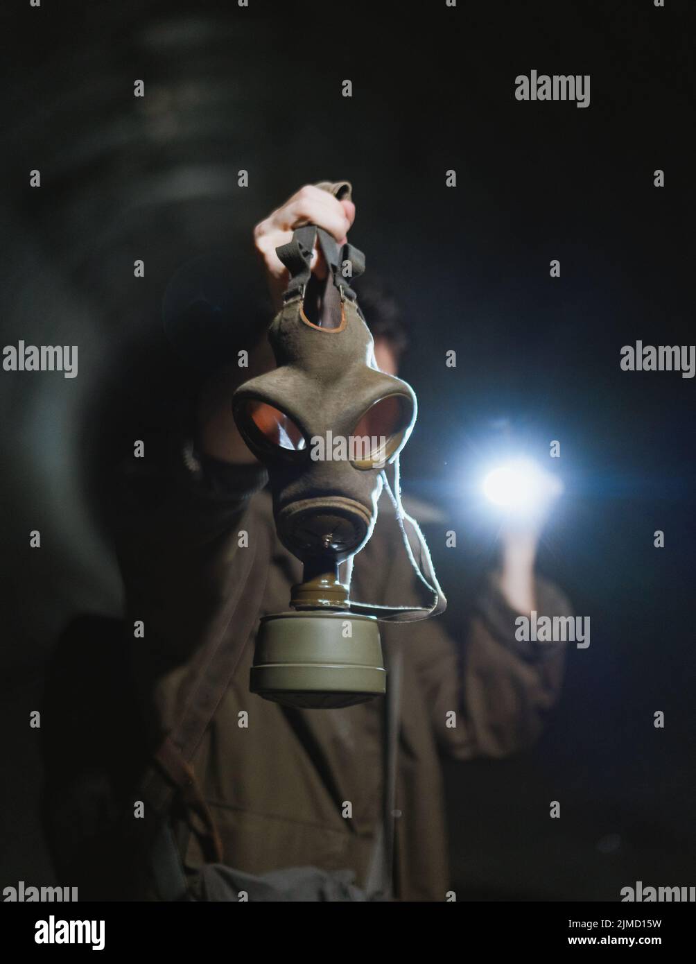 Unrecognizable male explorer in gas mask illuminating dark underground ...