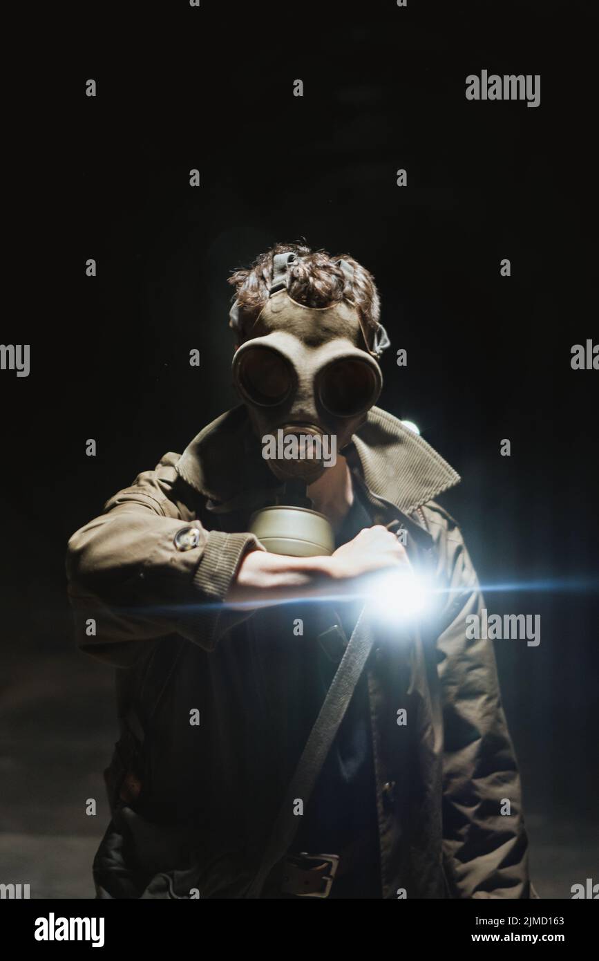 Full body unrecognizable male explorer in gas mask illuminating dark ...