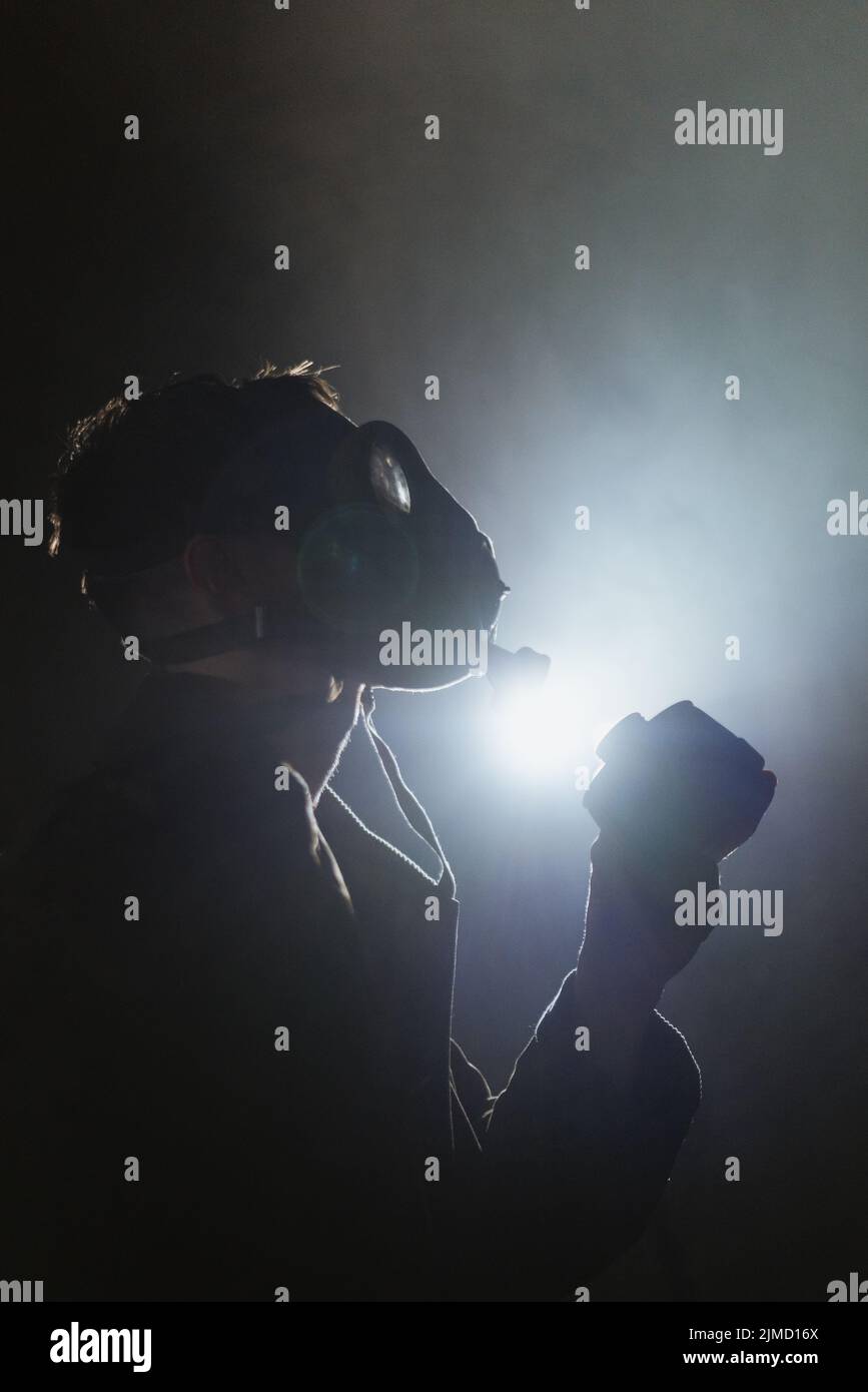 Side view of unrecognizable man in gas mask changing filter while ...