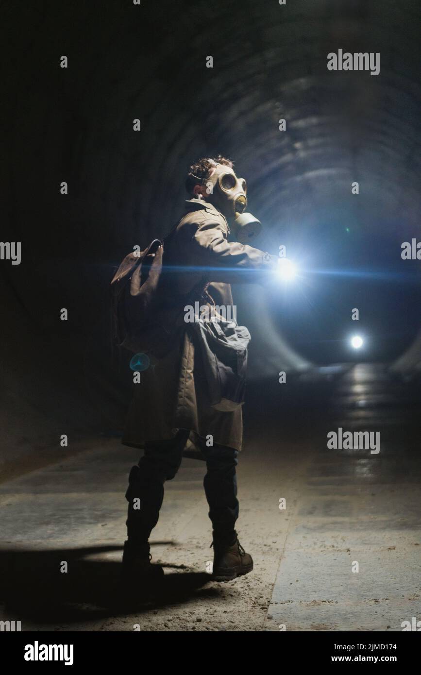 Full body unrecognizable male explorer in gas mask illuminating dark ...