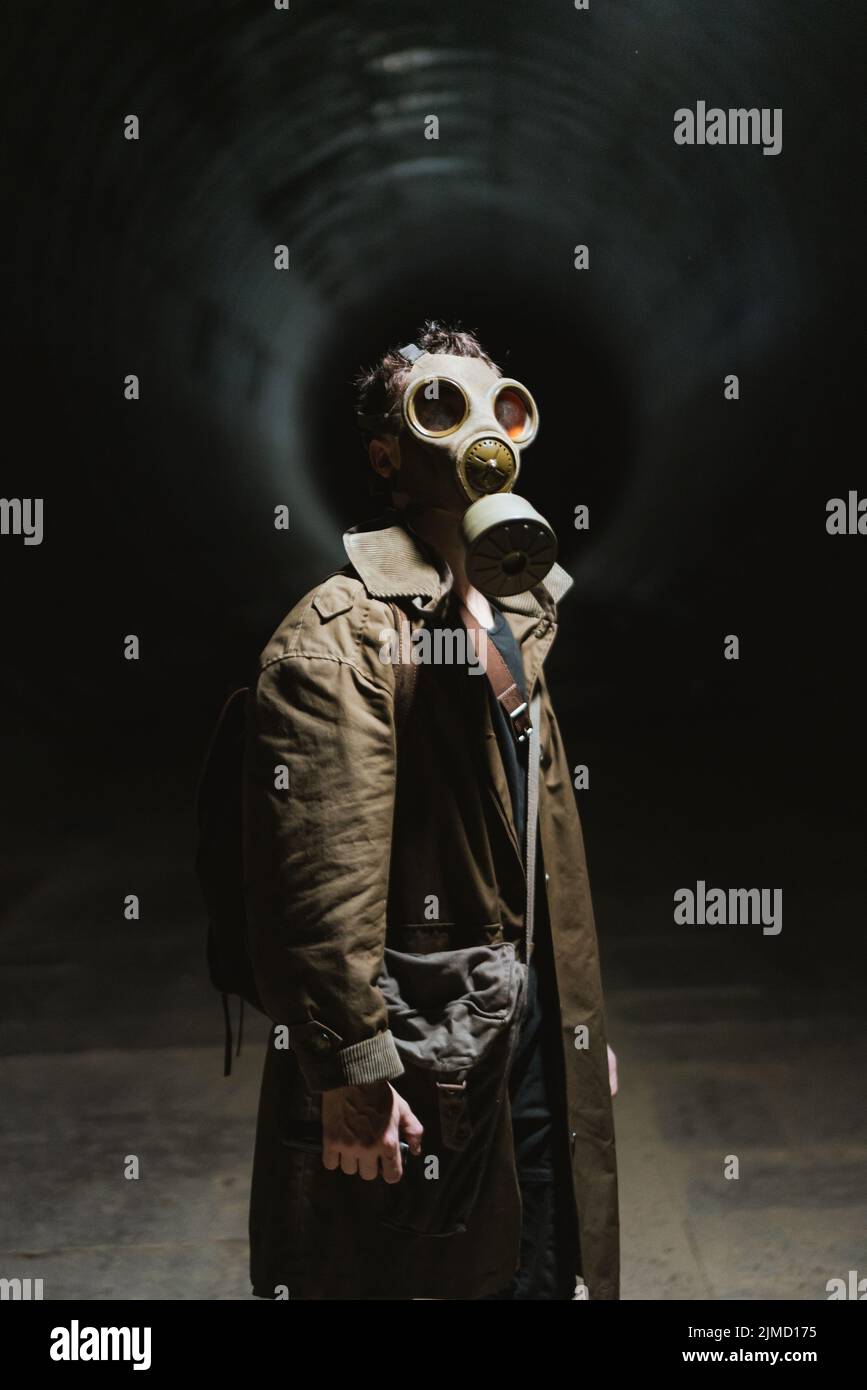 Side view of unrecognizable male explorer in gas mask in dark ...