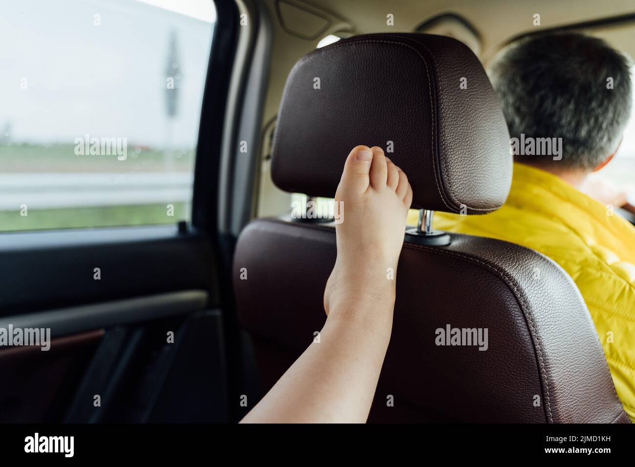 Crop unrecognizable barefooted kid rising leg and leaning on window ...