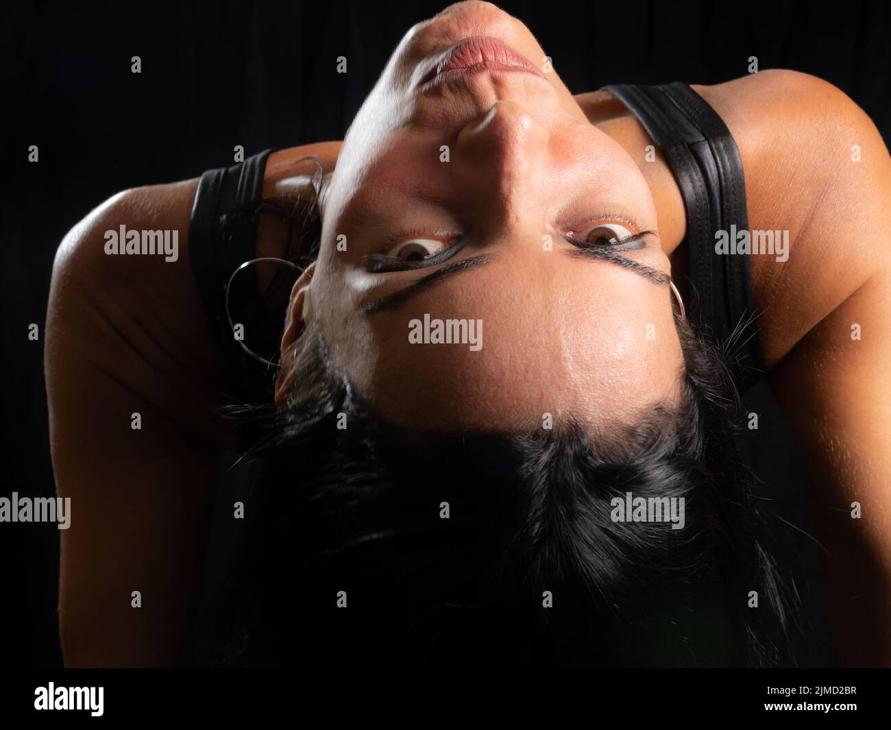 Studio portrait of young woman looking at camera against simple studio ...