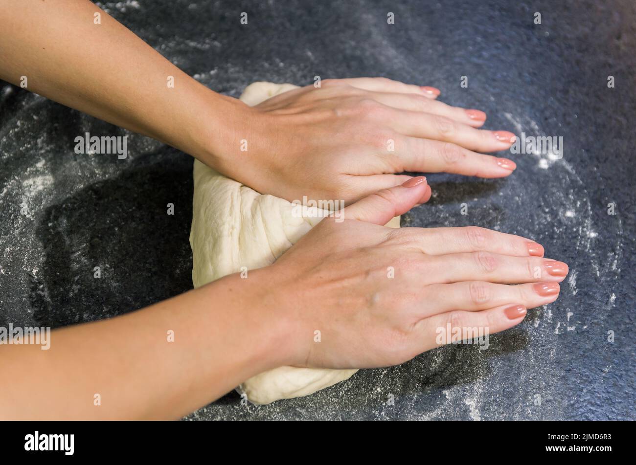 Woman preparing pizza dough on black granite table Stock Photo - Alamy