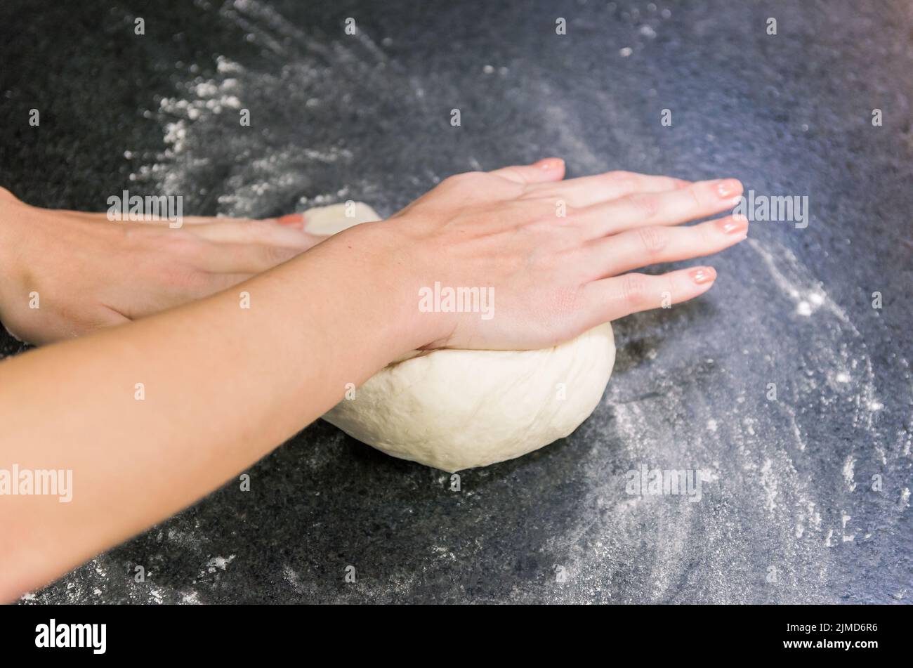 Woman preparing pizza dough on black granite table Stock Photo - Alamy