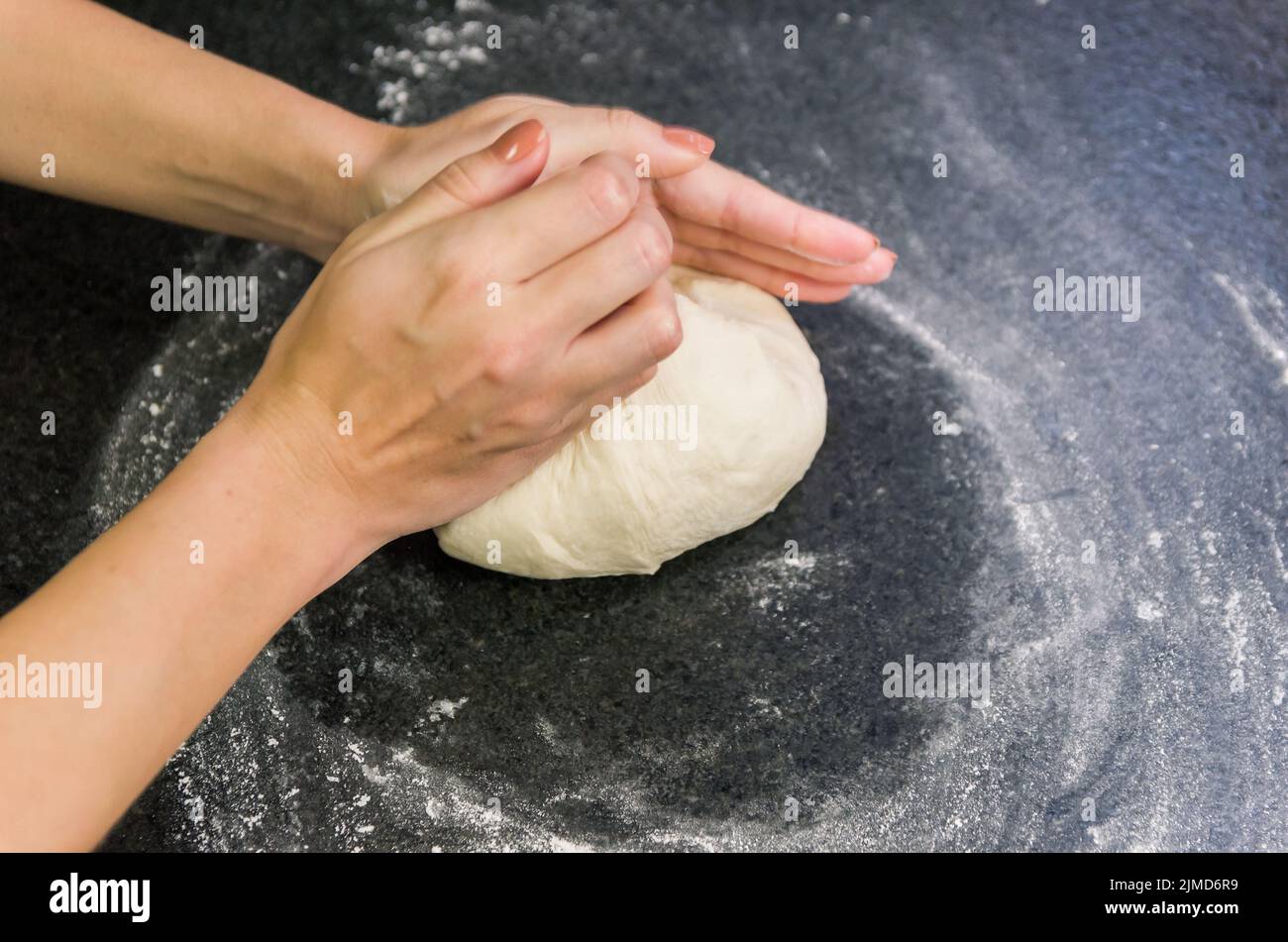 Woman preparing pizza dough on black granite table Stock Photo - Alamy