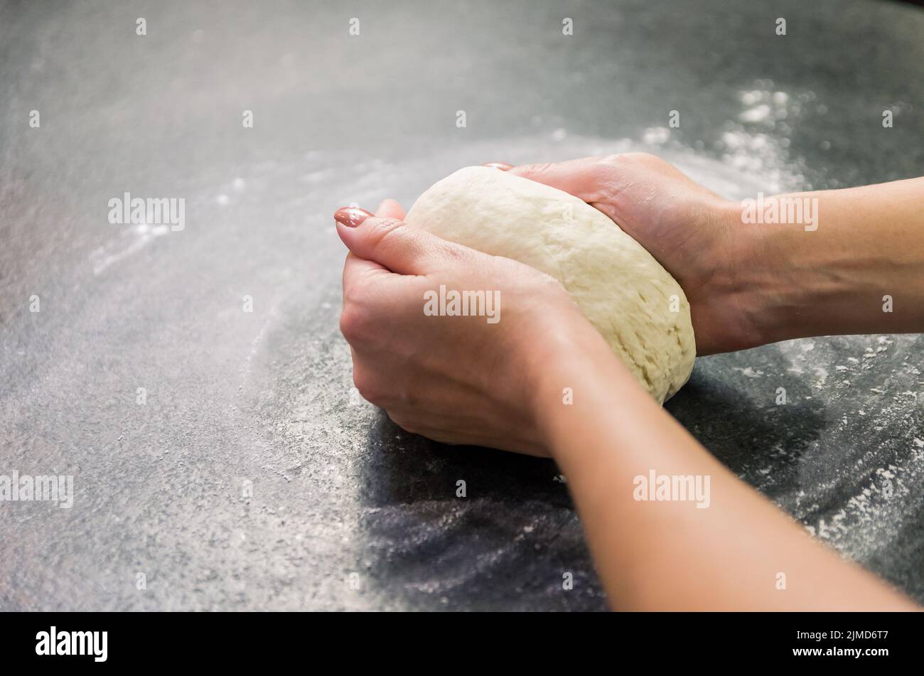 Woman preparing pizza dough on black granite table Stock Photo - Alamy