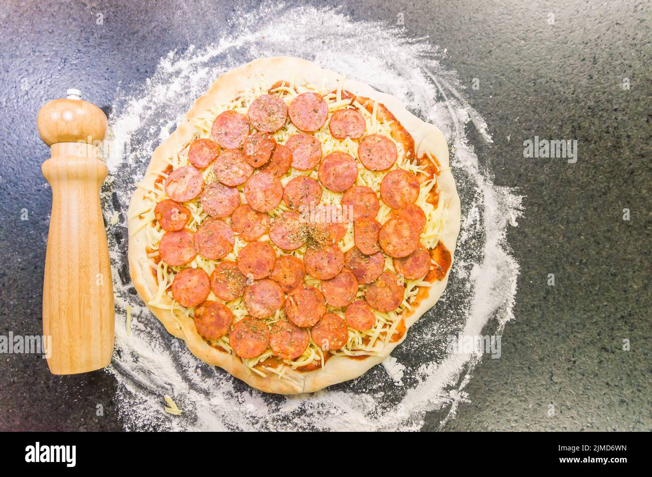 Preparing pepperoni pizza on black granite table Stock Photo - Alamy