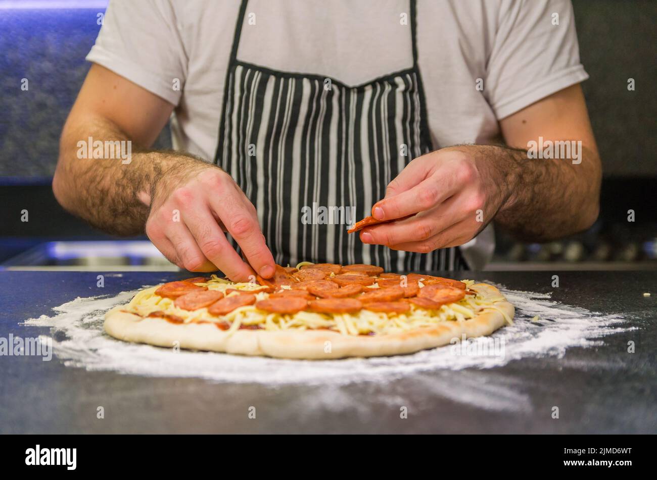 Man preparing pepperoni pizza on black granite table Stock Photo - Alamy