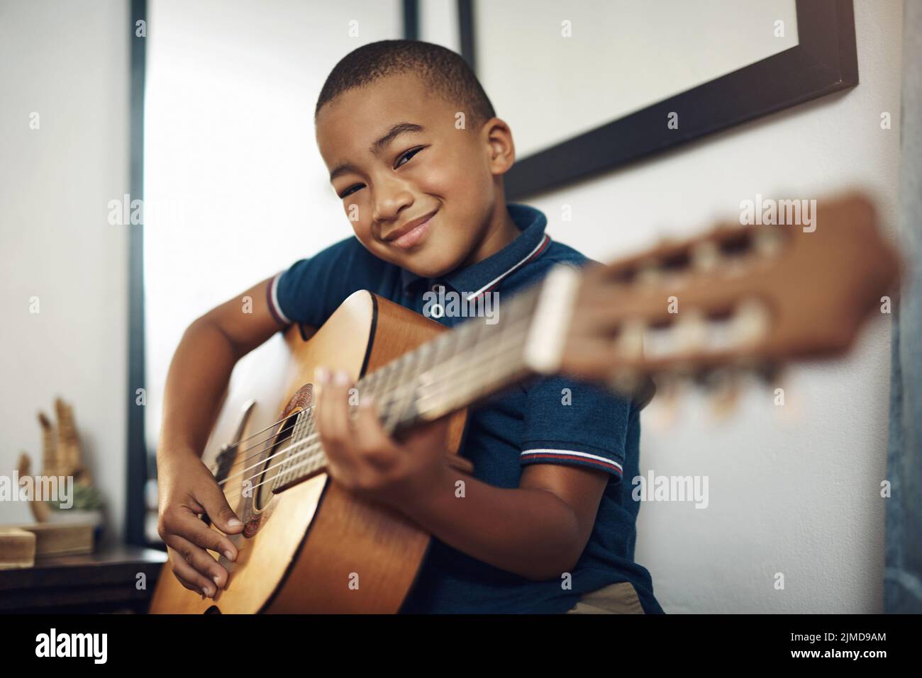 Im having so much fun learning to play the guitar. a young boy playing ...