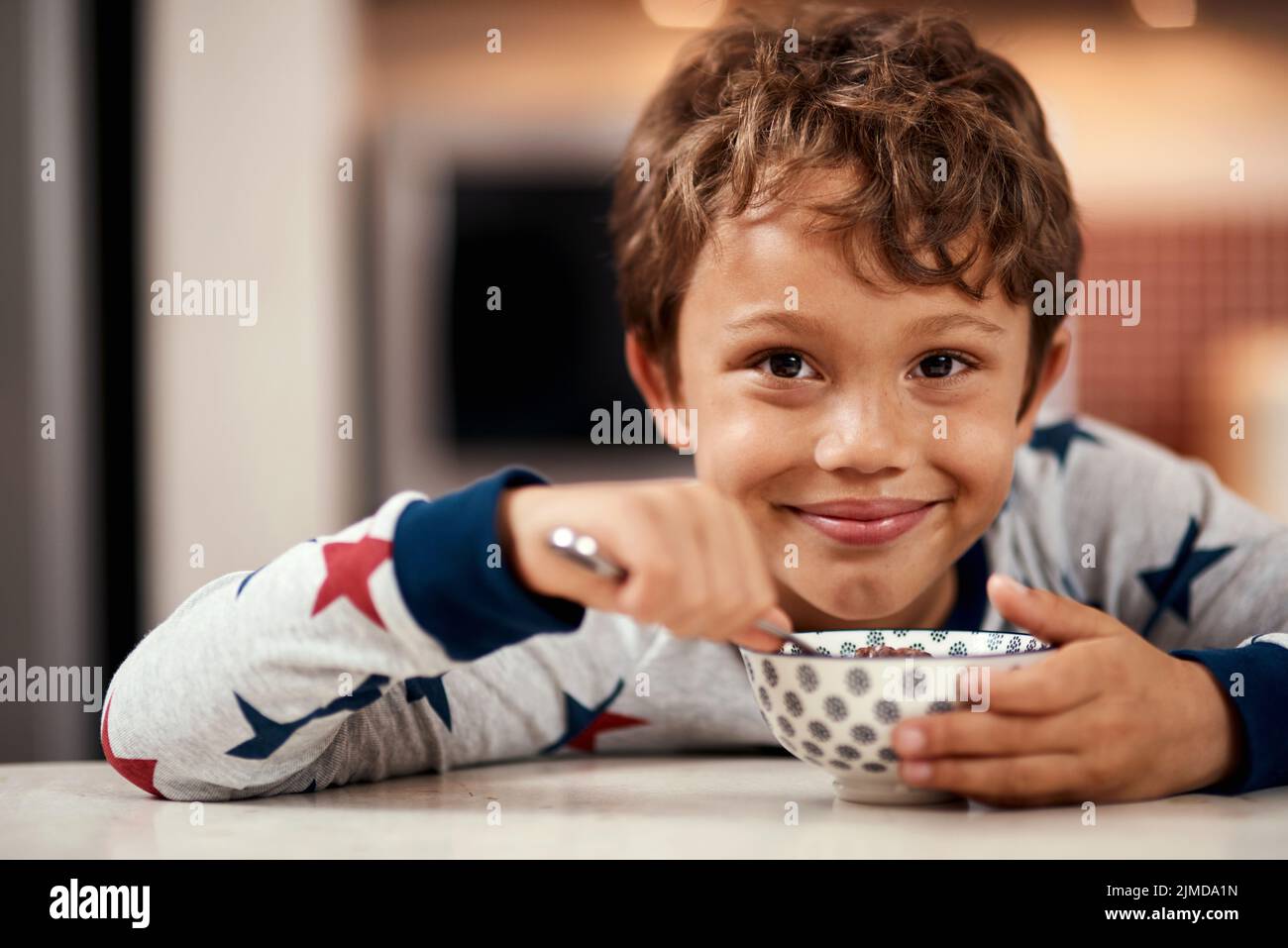 Breakfast is the happiest meal of the day. a young boy eating cereal at ...