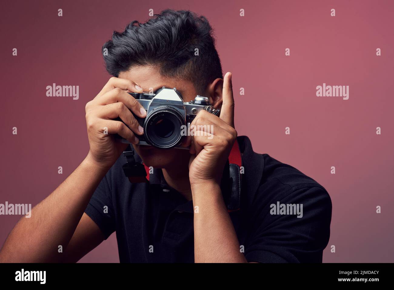 Lets get you on camera. Studio shot of a young man holding up a camera ...