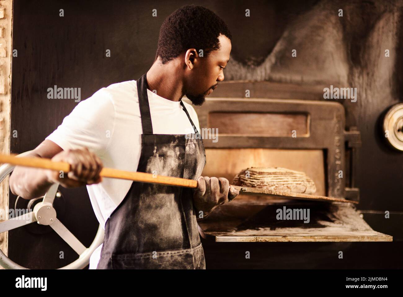 I make them fresh every day. a male baker removing freshly baked bread ...
