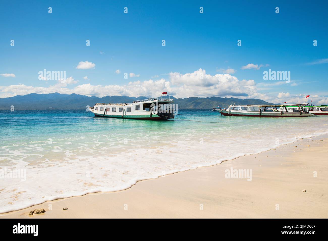 Gorgeous daytime view of sandy beach, boats and the island of Lombok ...