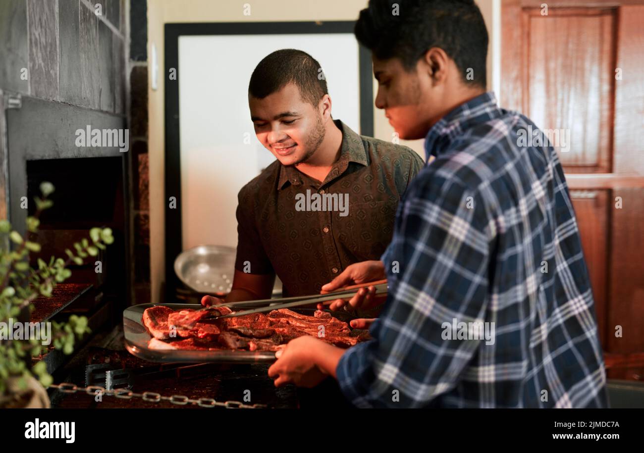 Chilling and grilling together. two young men grilling meat while ...