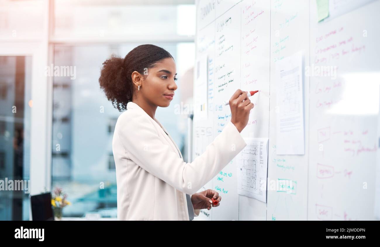 Young businesswoman planning on a whiteboard in modern office and ...