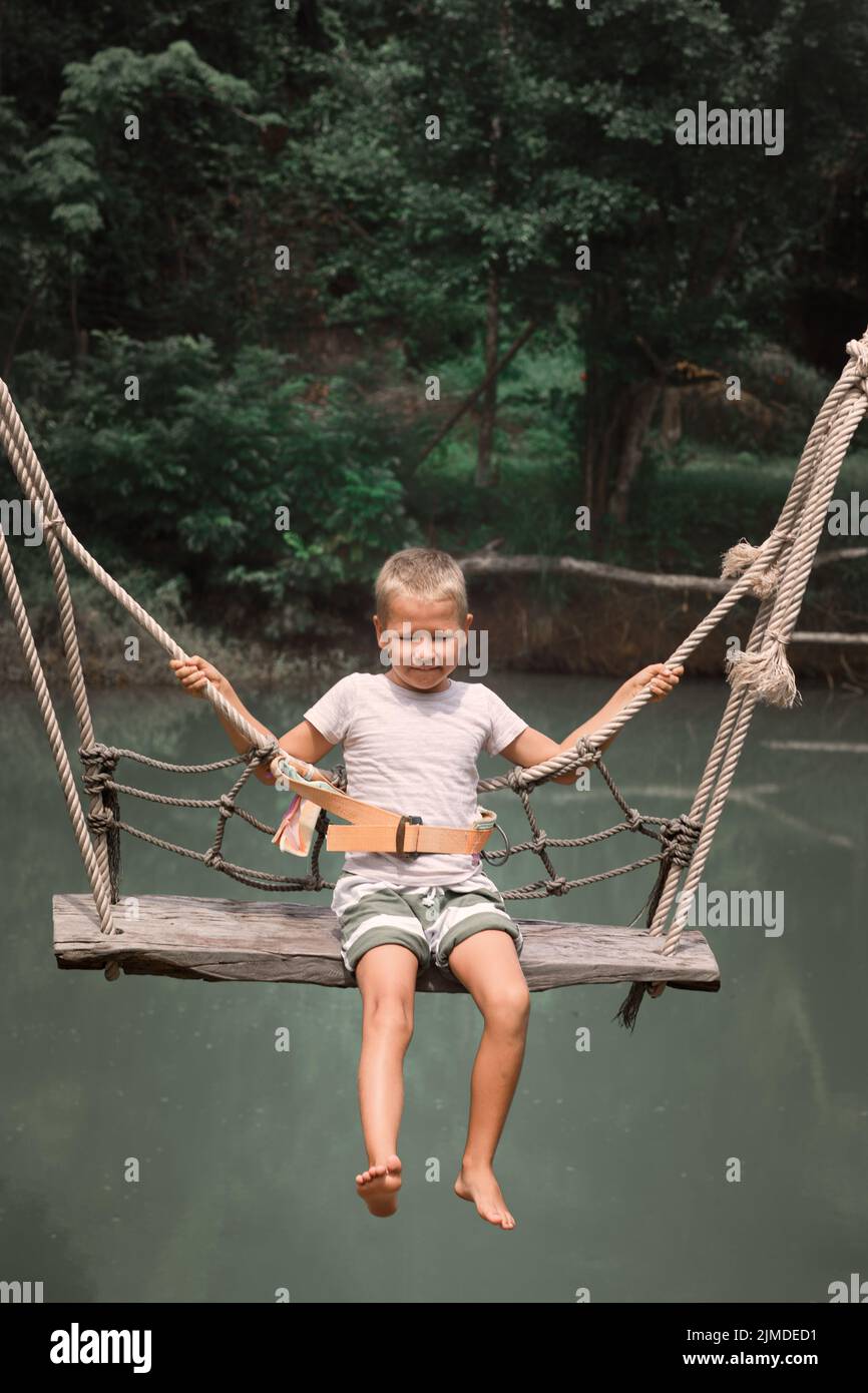 Boy swinging on a swing over the river Stock Photo - Alamy