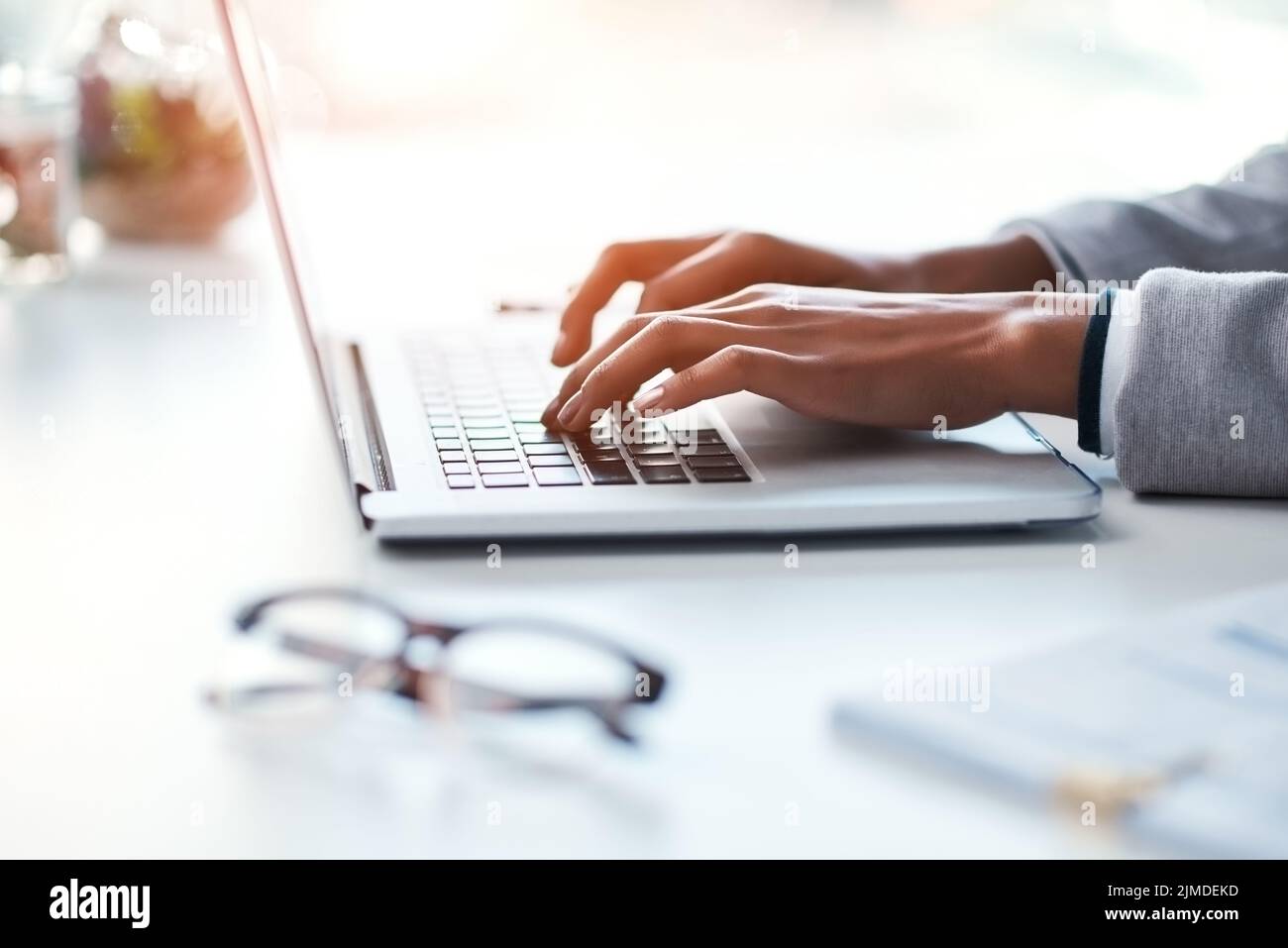 Businesswoman typing work on a laptop at her desk in a modern office ...