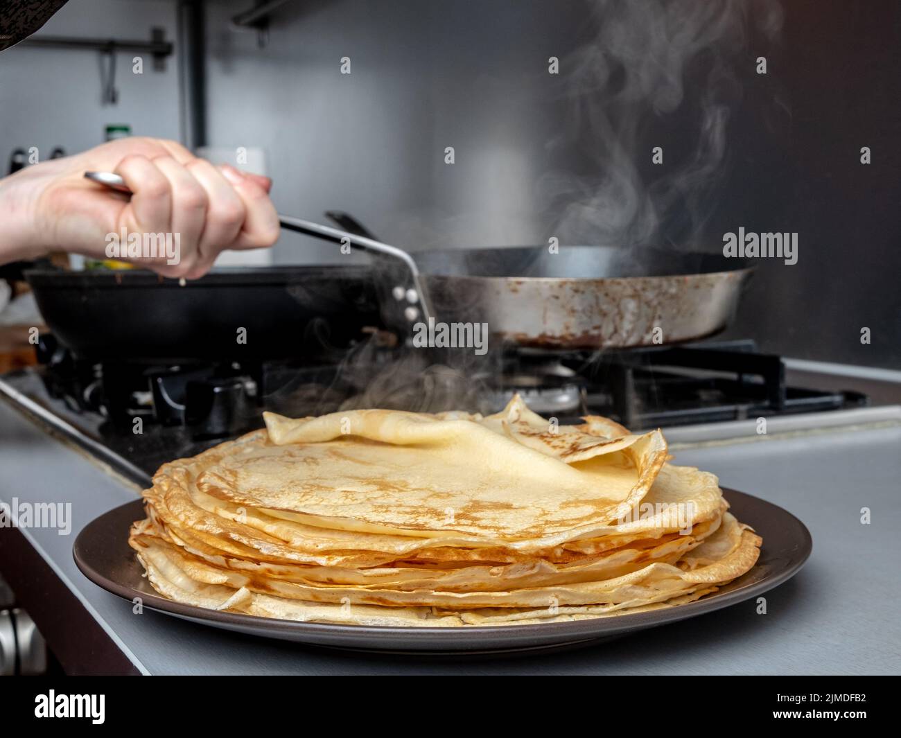 Freshly baked pancakes stacked on a platter from which steam comes ...