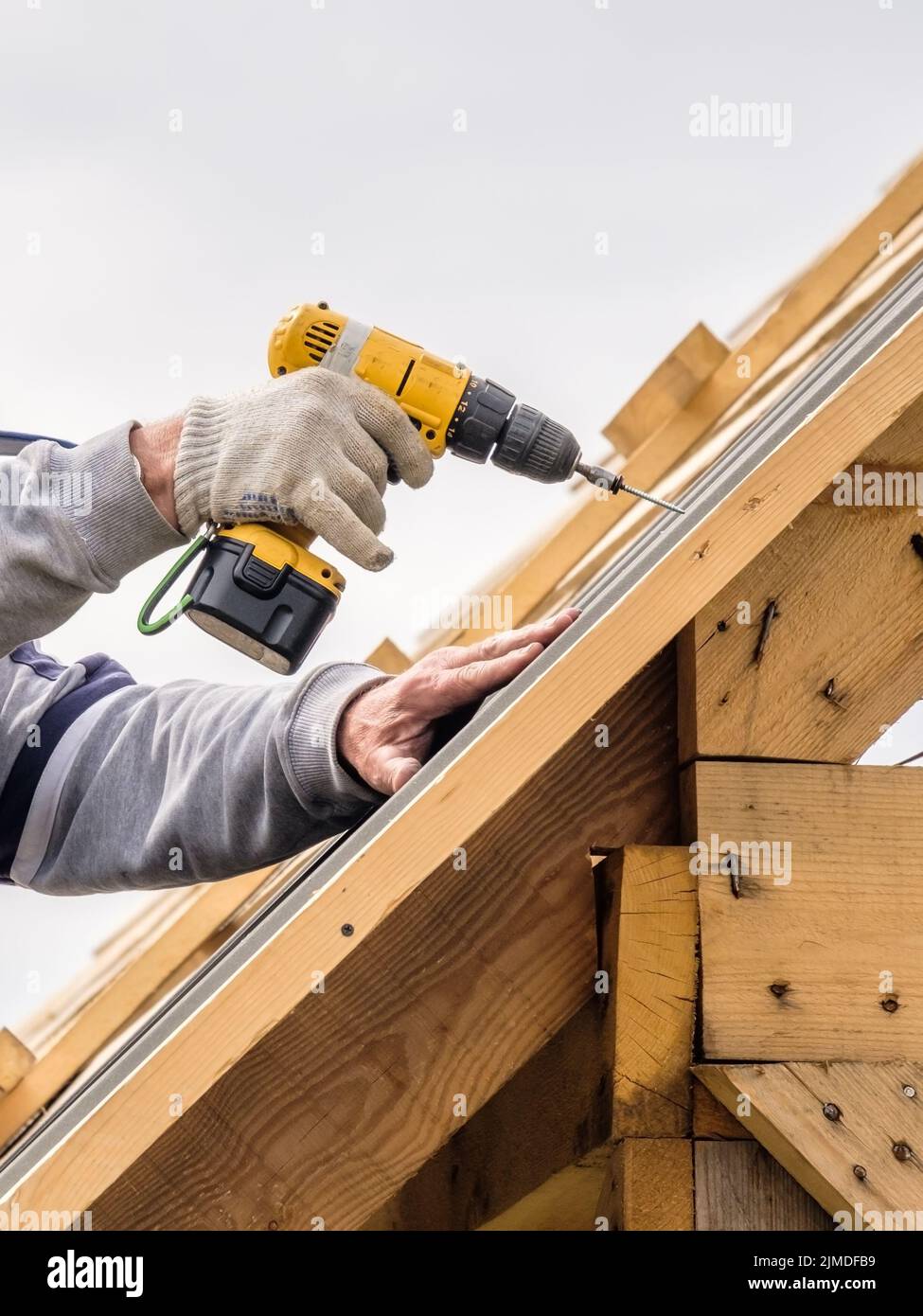 Male hands in gloves with a screwdriver screw the roofing sheet to the ...