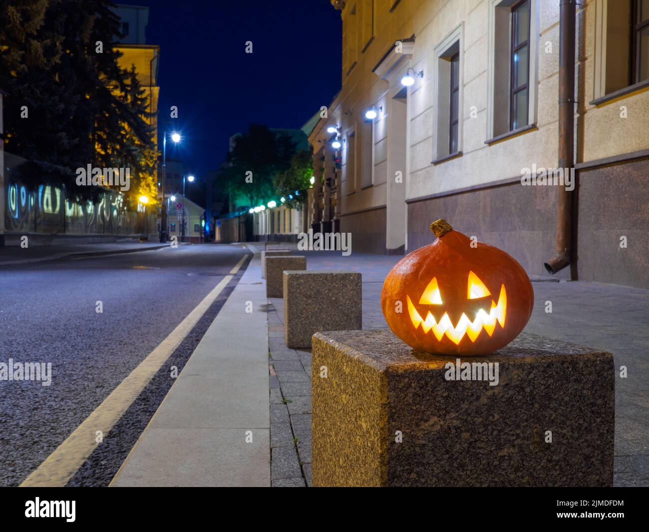 Halloween pumpkin on a deserted city street at night. Blurry colored ...